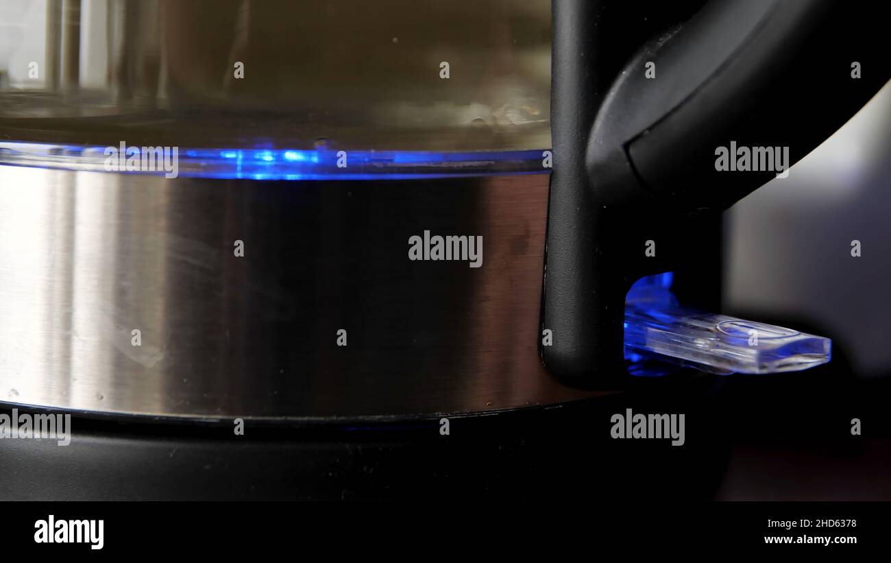 Male finger pressing the power switch on the electric kettle. Close up ...