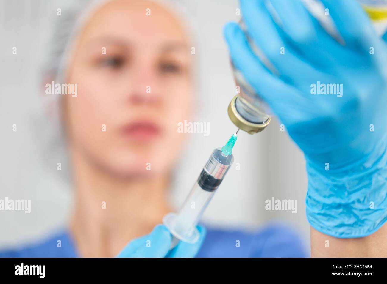 Young female health worker fills a syringe with saline for injection in ...