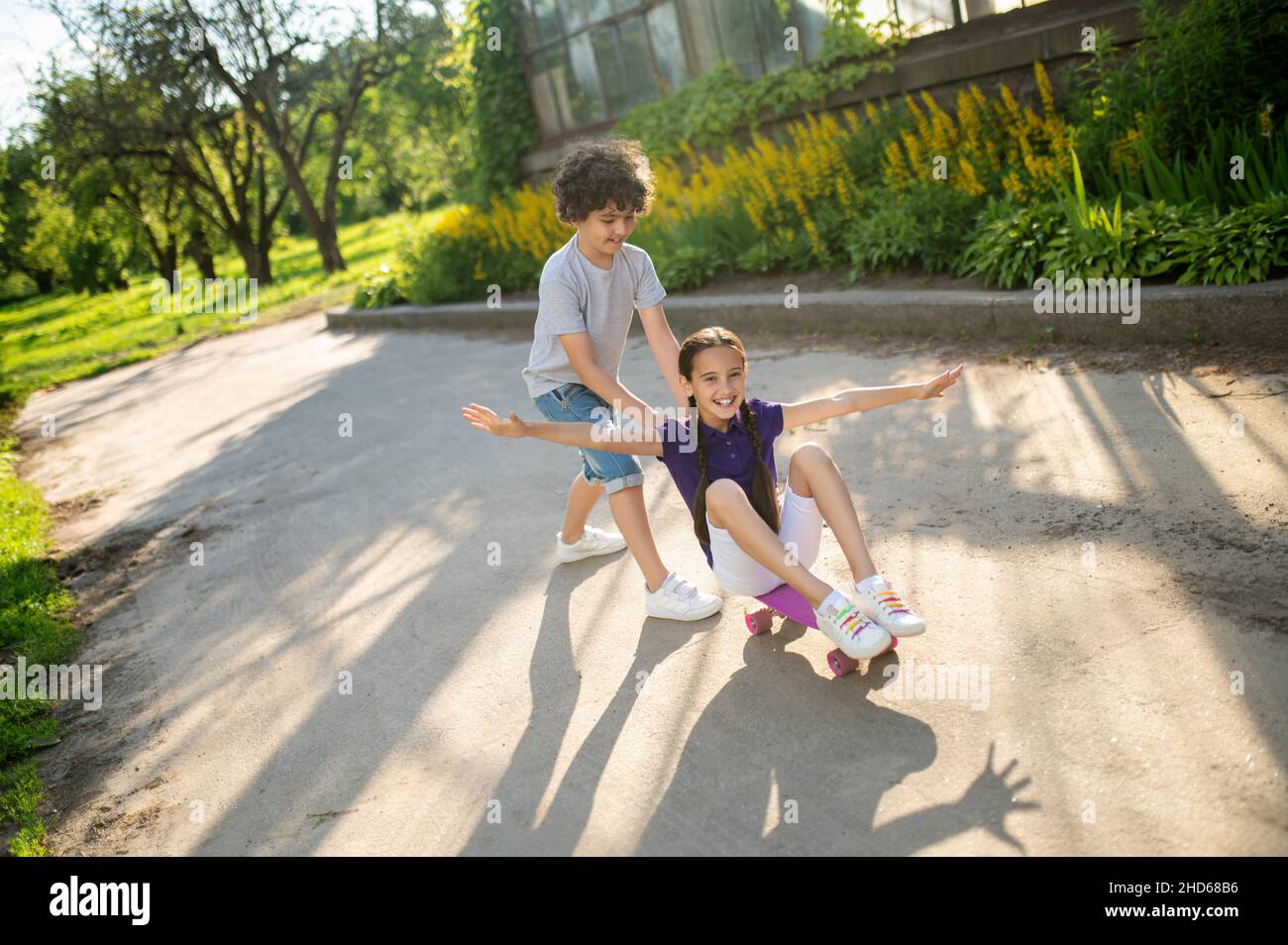 Boy teaching a girl how to skateboard Stock Photo - Alamy
