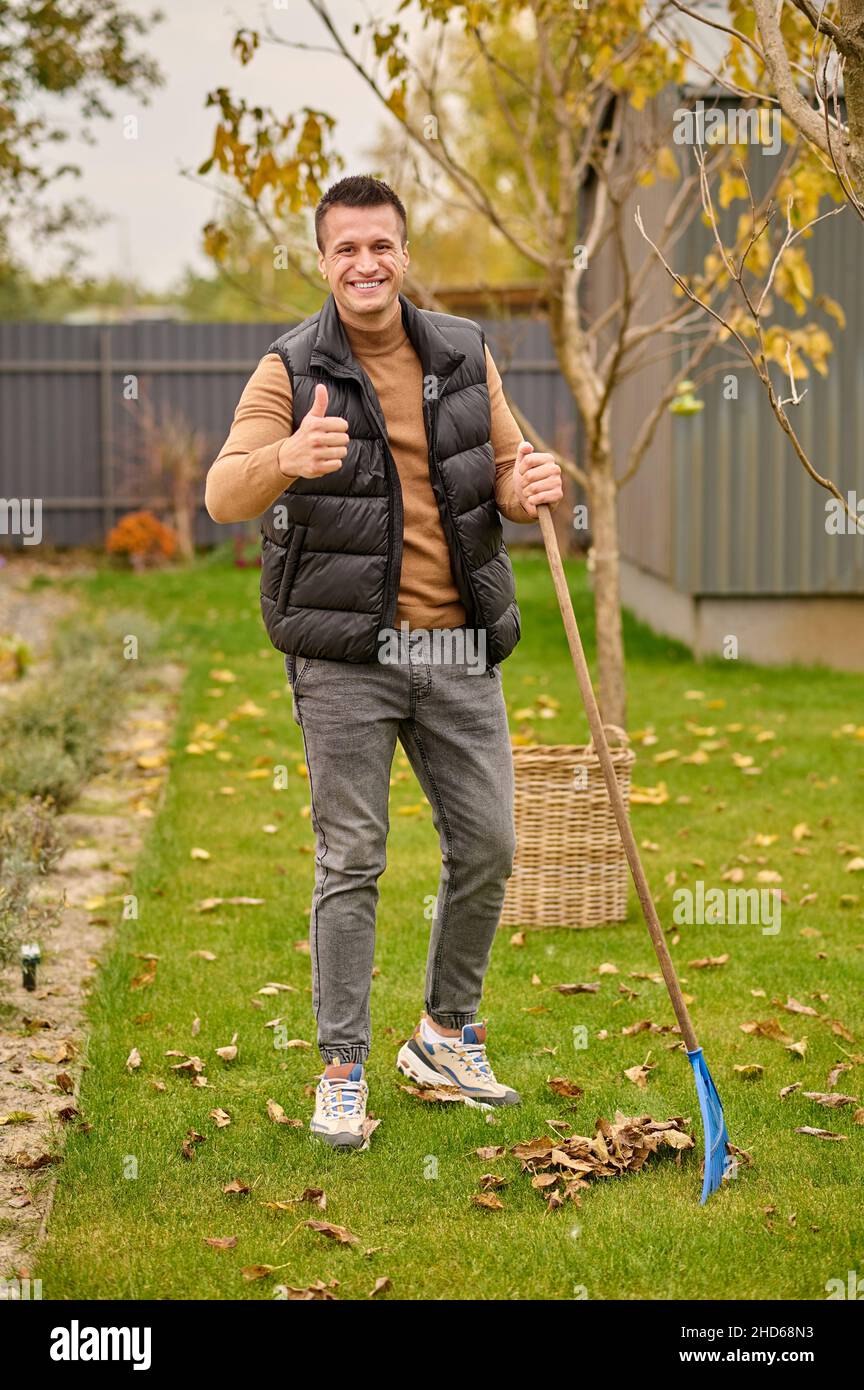 Man standing with rake showing ok gesture Stock Photo - Alamy
