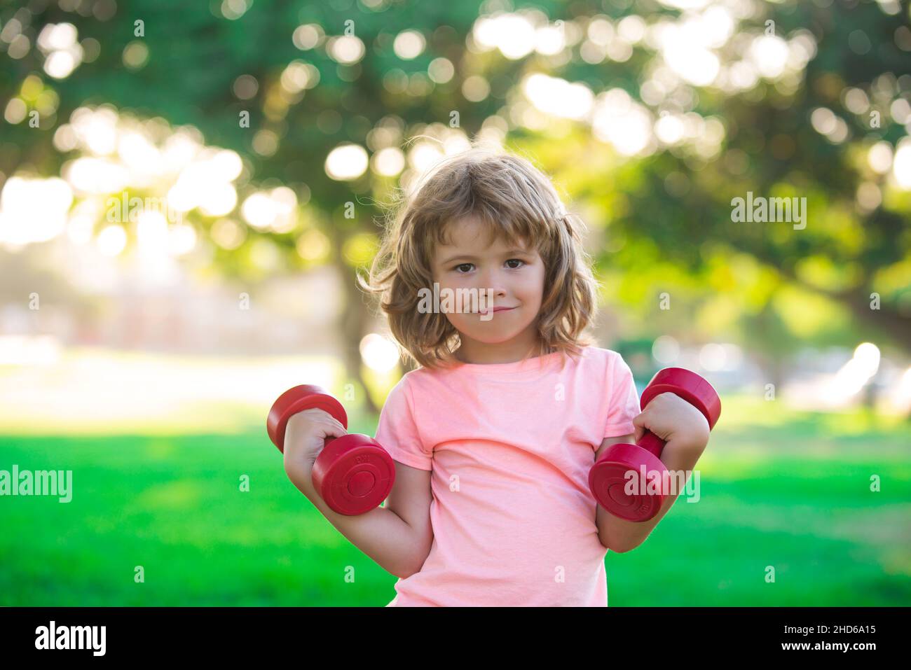 Sport child boy with strong biceps muscles. Kids exercising fitness dumbbells. Strong little boy ...
