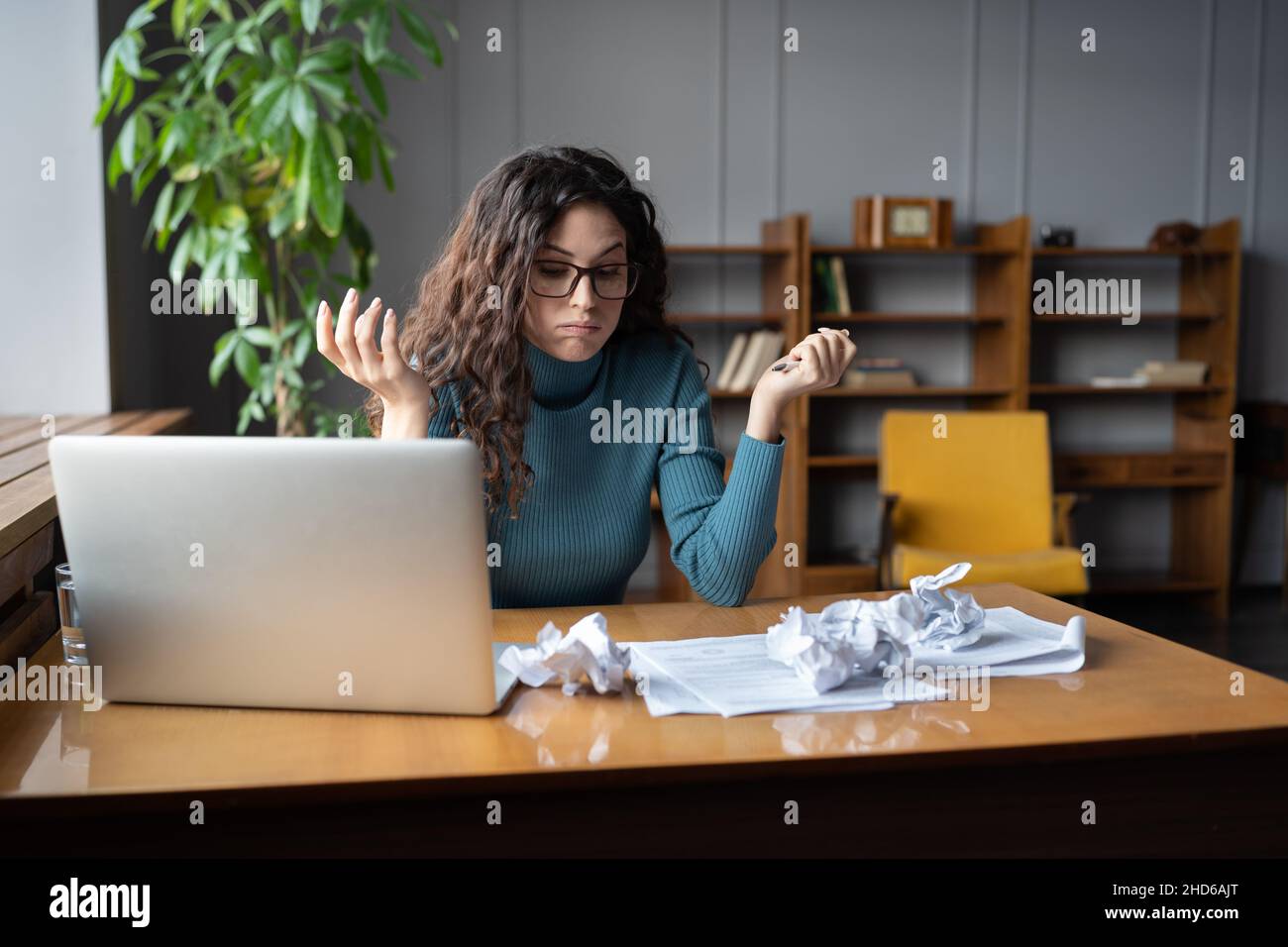 Stressed businesswoman sitting at office desk with crumpled paper, cant ...