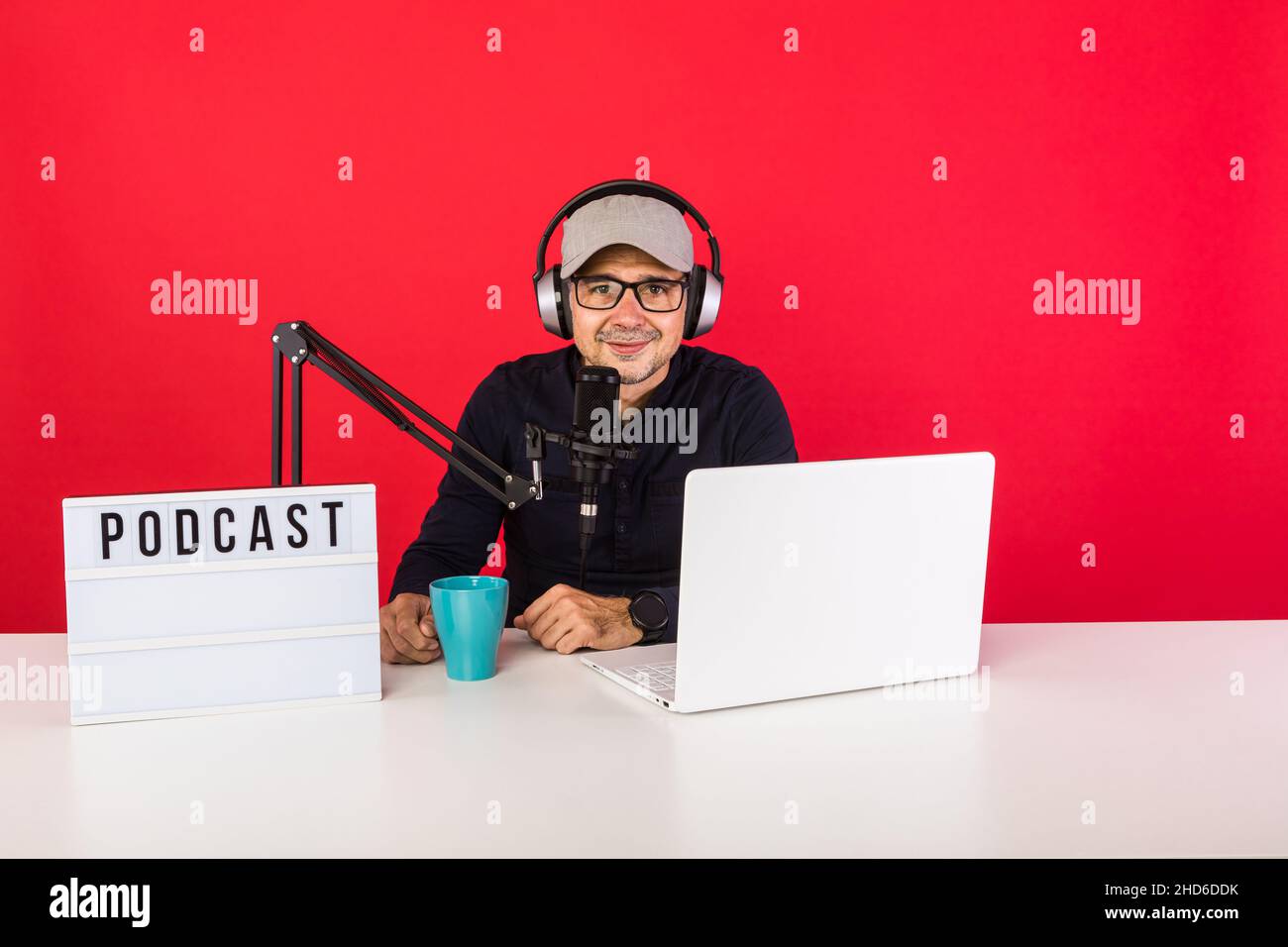 Male presenter with cap in podcast radio recording studio smiling, next ...