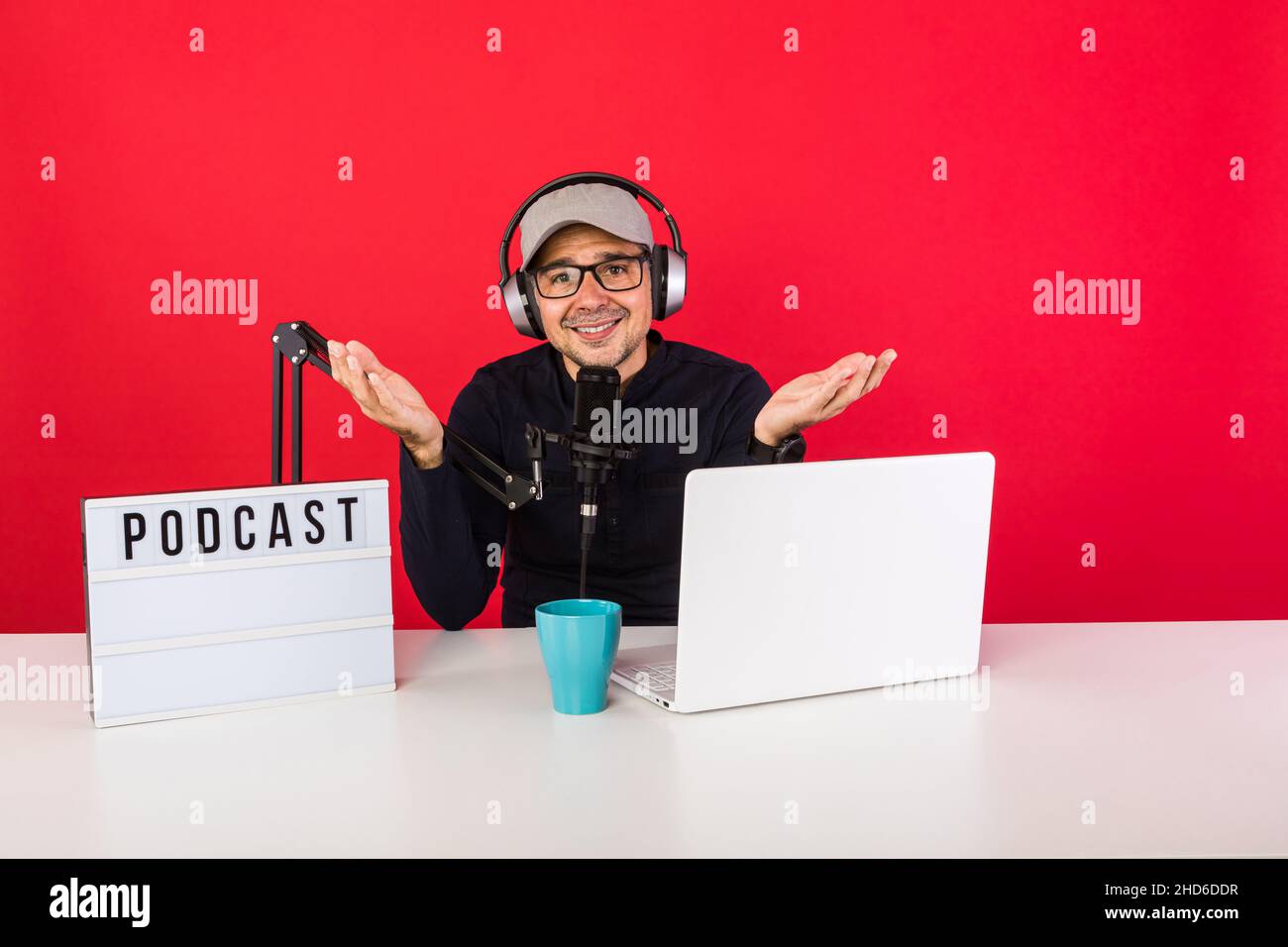 Man presenter with cap in podcast radio recording studio making hand ...