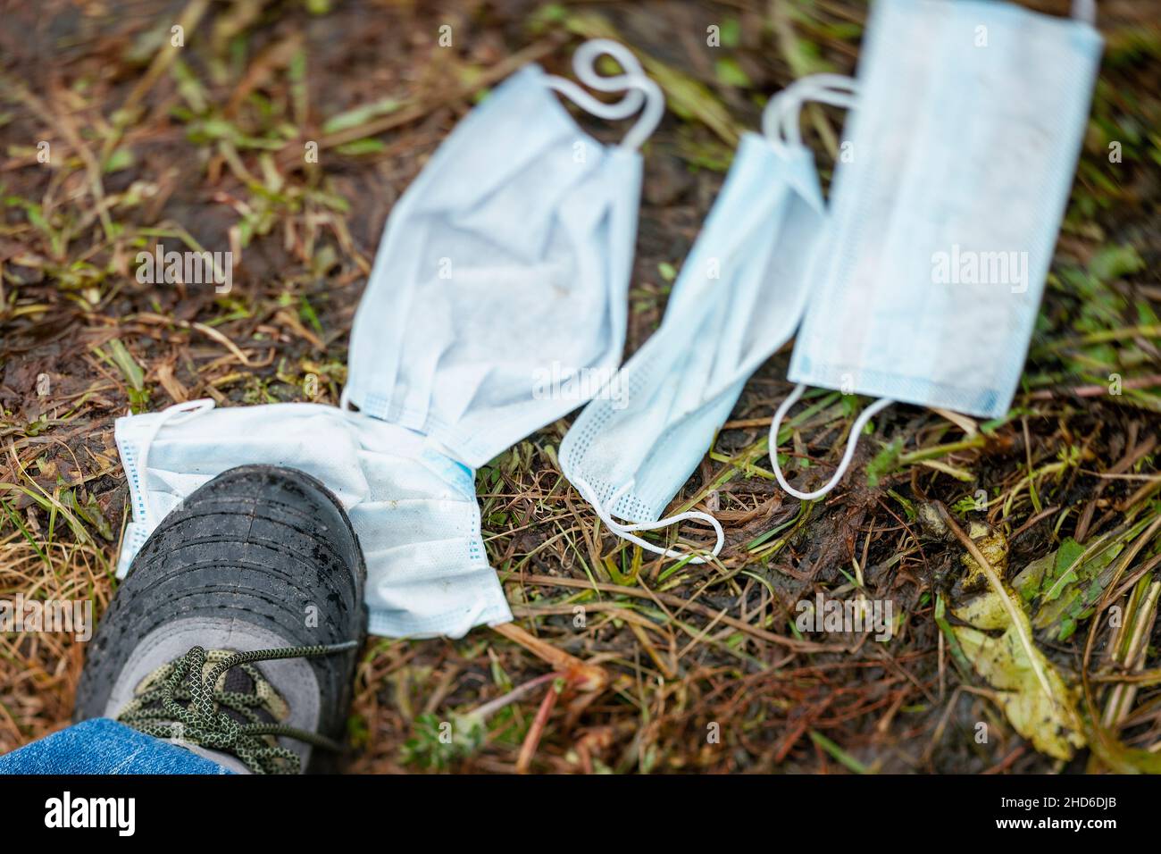 a foot wearing boot steps over medicine masks abandoned on the ground ...