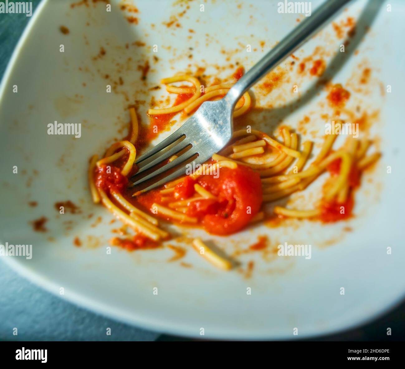 a messy plate with finished spaghetti with tomatoes and fork Stock ...