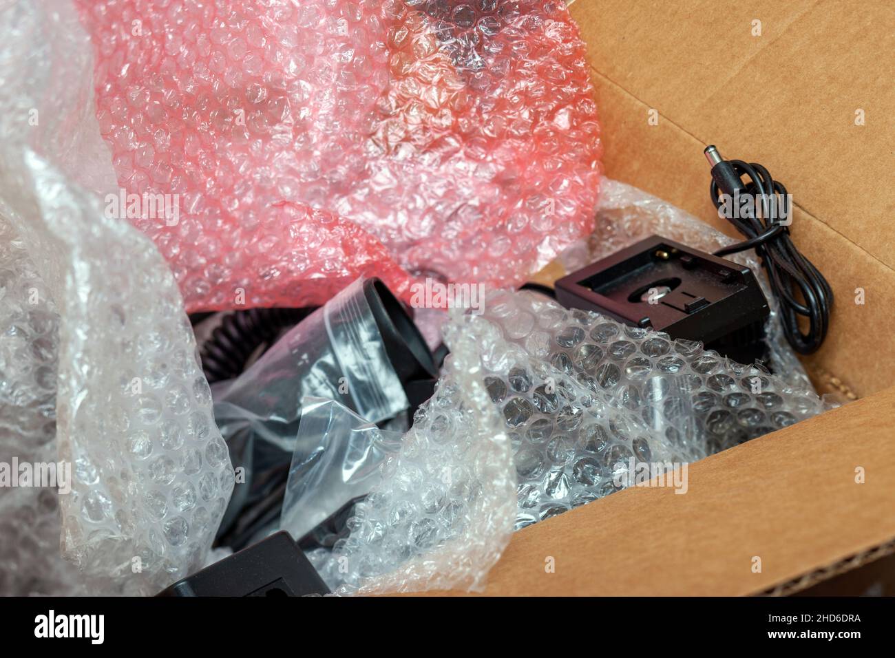 Open cardboard box with home appliances wrapped in film, indoor closeup ...