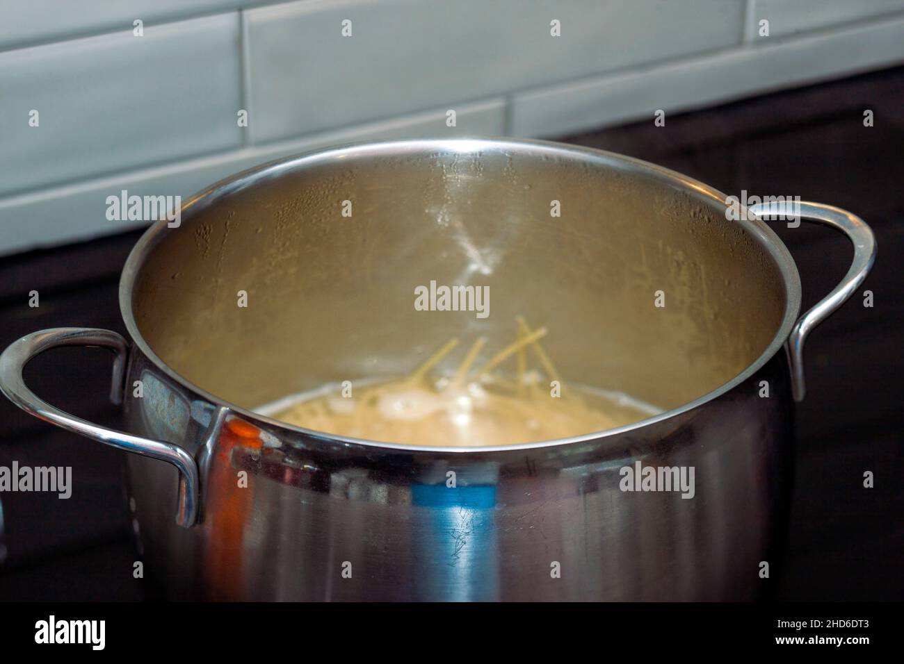 a stainless casserole with spaghetti in boiling water, indoor closeup ...