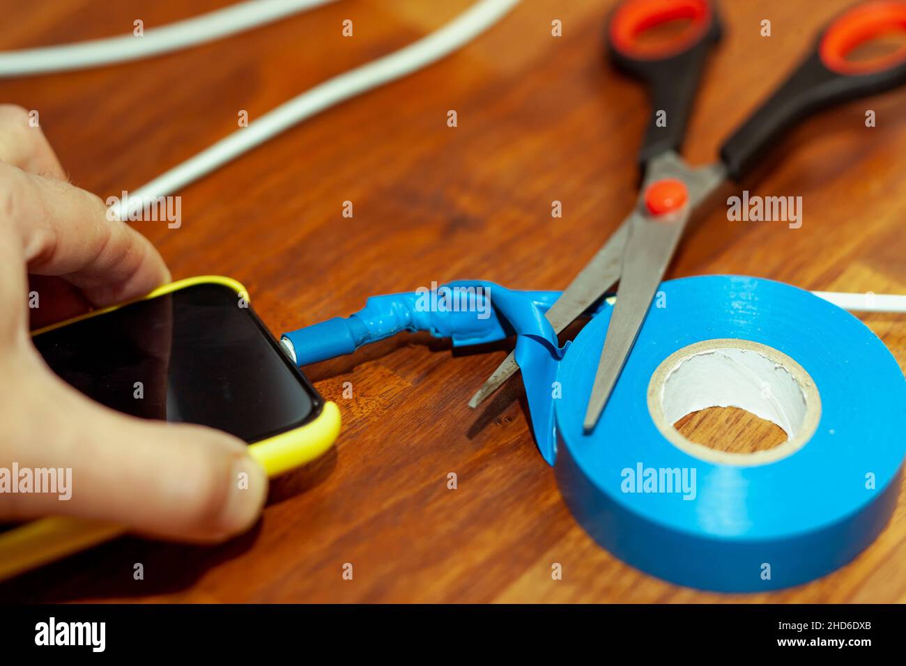 a hand of diy man fixing mobile phone charger with adhesive tape ...