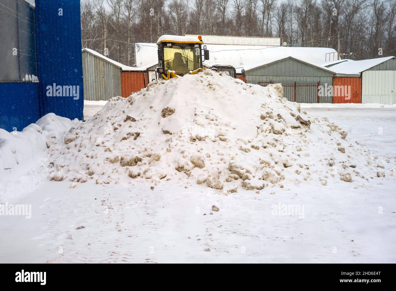 A pile of dirty snow and a tractor behind it, industrial landscape ...