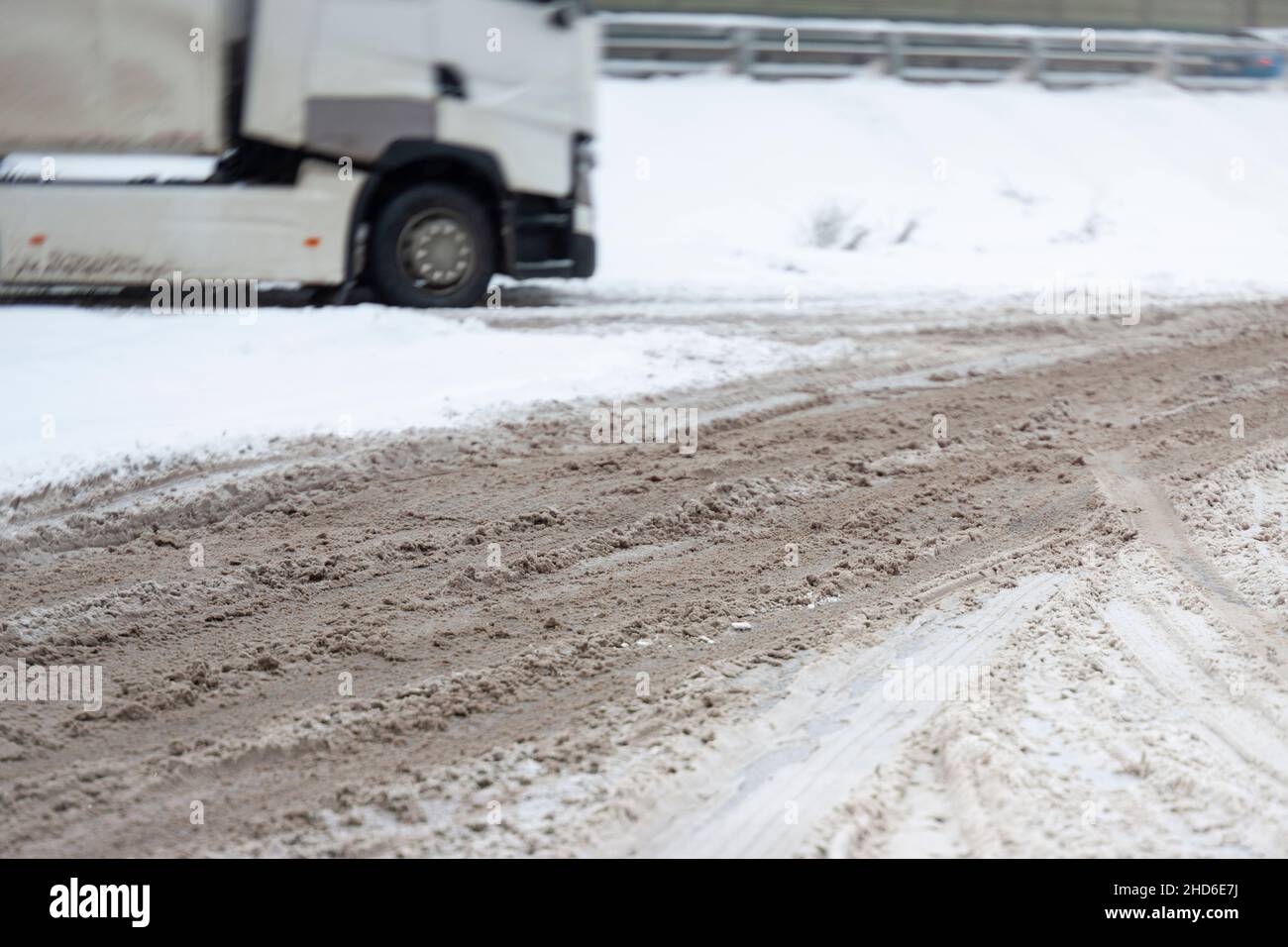 dirty sludgy road and truck in the blurred background, winter scene ...