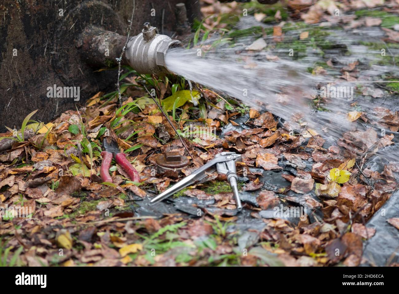 Closeup of a burst pipeline and tools scattered on the ground Stock ...