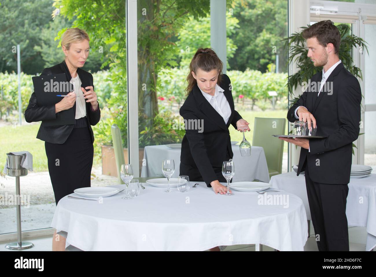 group of waiters and manager preparing tables before event Stock Photo ...