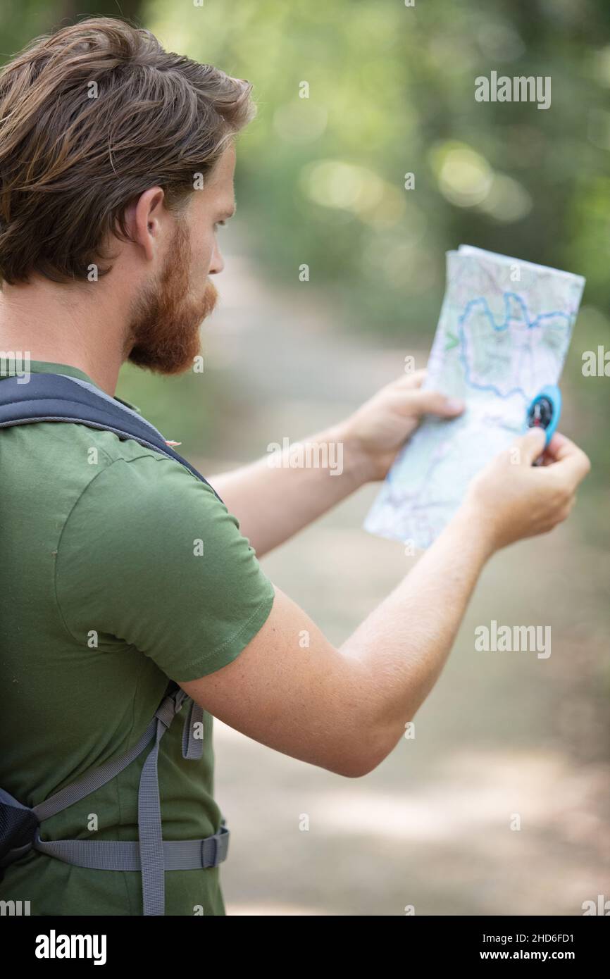young handsome hiker using map and compass in the nature Stock Photo ...