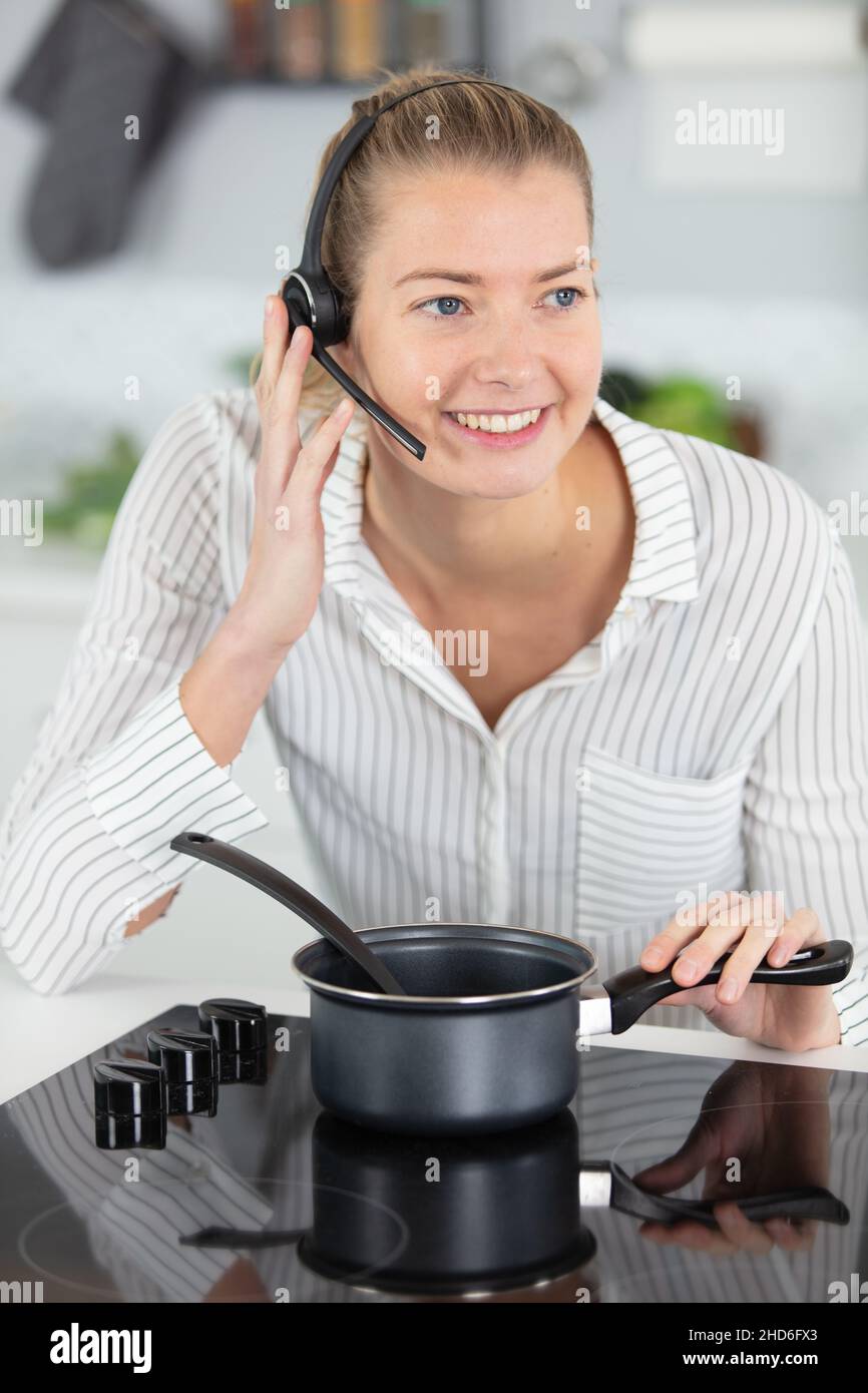 young business woman working while cooking meal in kitchen Stock Photo ...