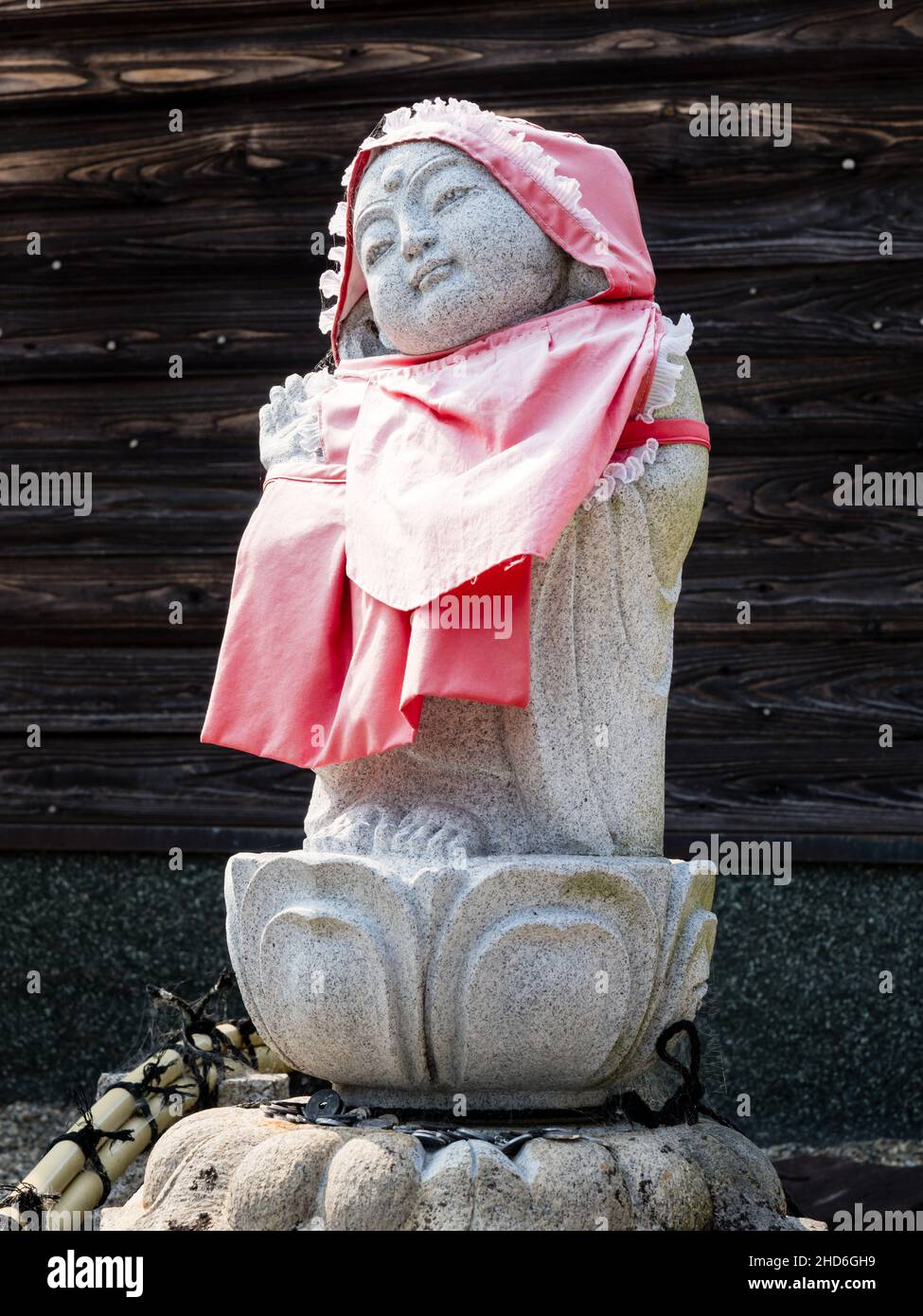 Japanese stone statue of Jizo with red clothes Stock Photo - Alamy