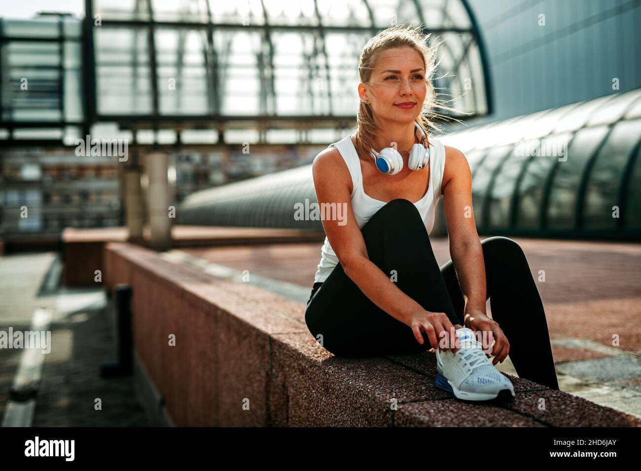 Beautiful young fit woman preparing to exercise outdoors. Sport people ...