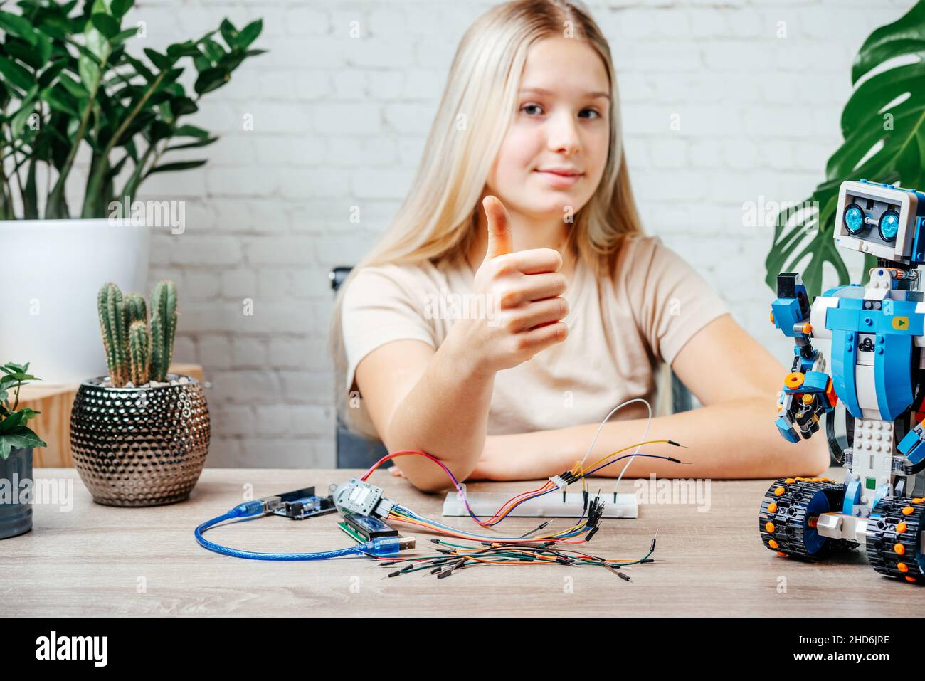 A teenager girl with her thumb up studying robotics at home, stem and ...
