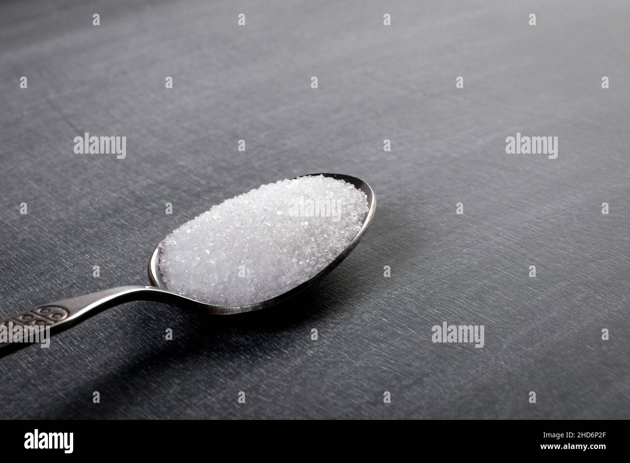 Teaspoon with white sugar on a chalk board background Stock Photo - Alamy