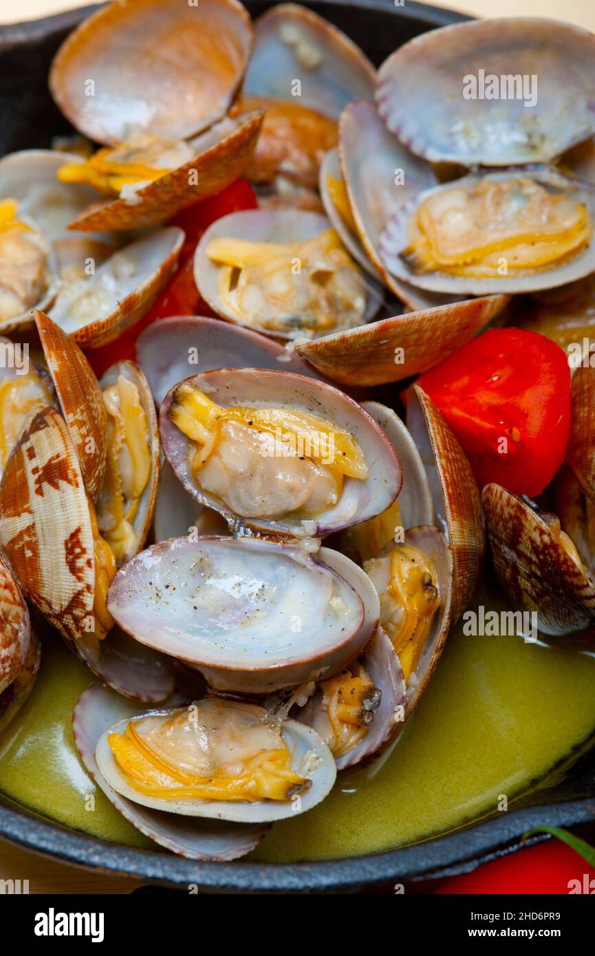 fresh clams stewed on an iron skillet over wite rustic wood table Stock ...