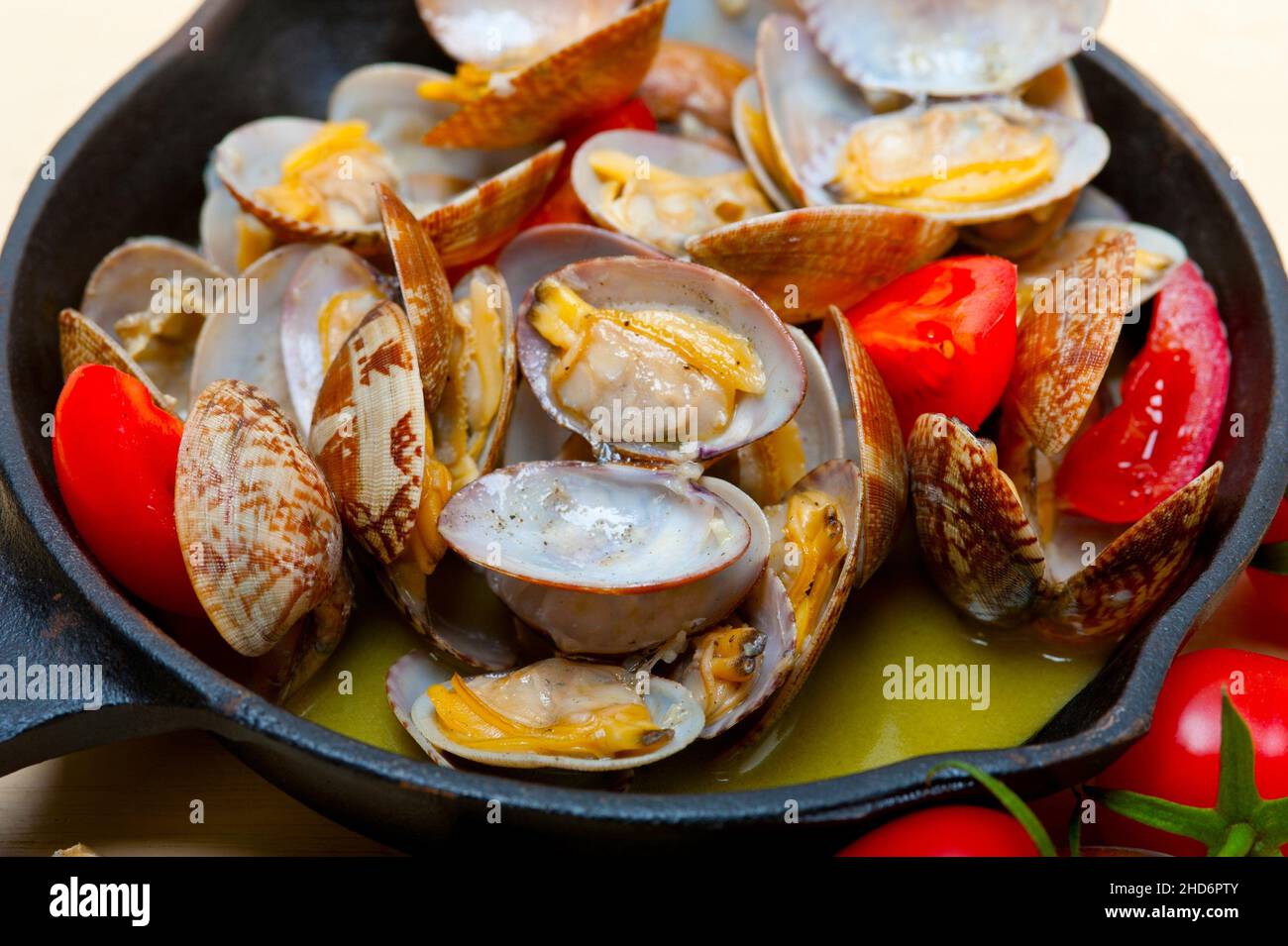 fresh clams stewed on an iron skillet over wite rustic wood table Stock ...