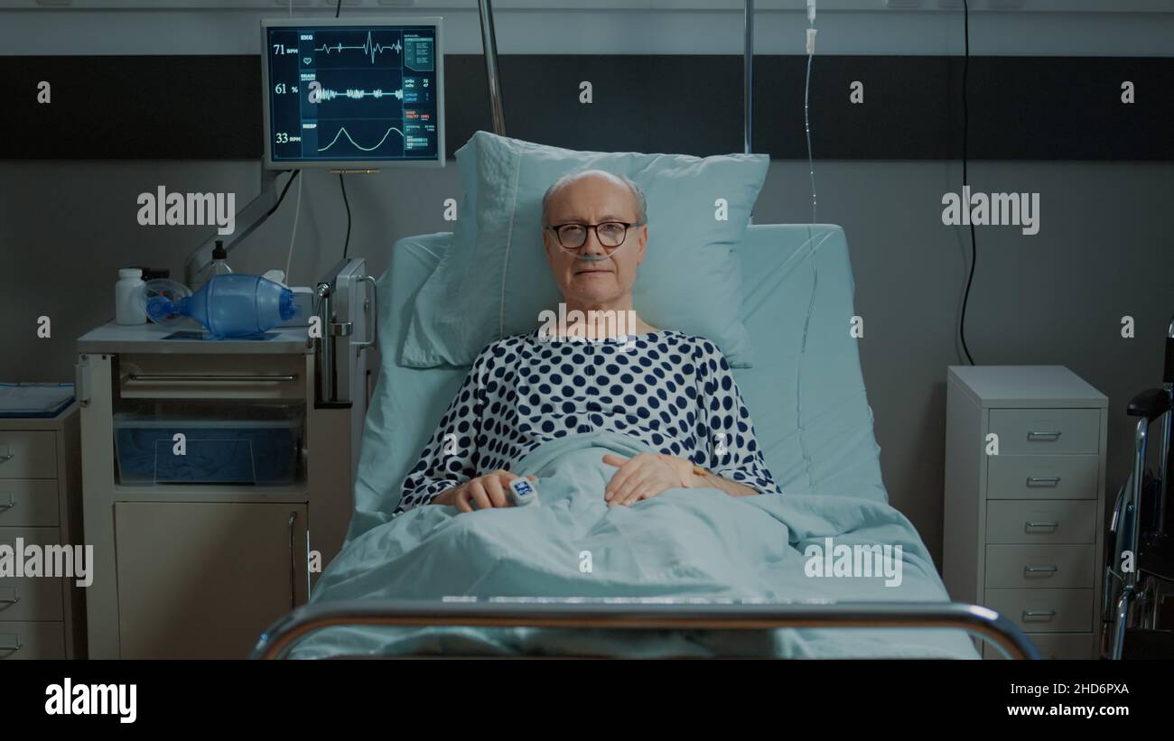 Portrait of sick patient staying in bed at hospital ward with oximeter ...