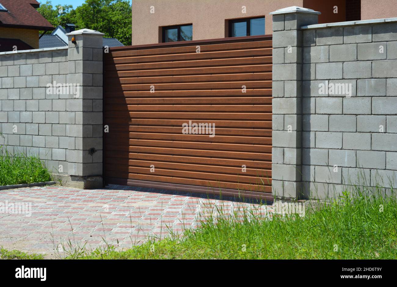 A close-up of a wood slat automatic sliding gate, entrance driveway ...