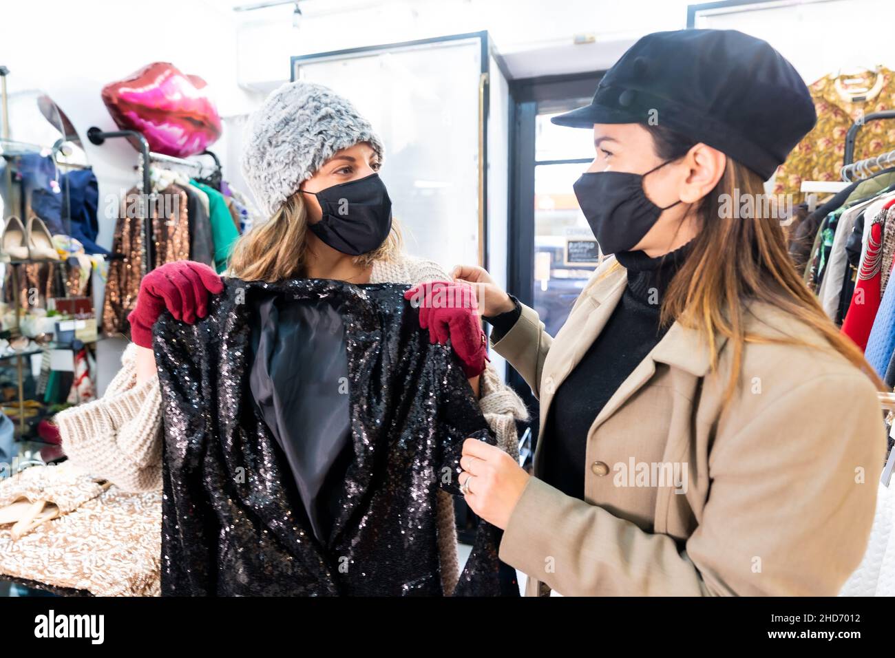 Employee of a luxury clothing store showing a sequin dress, security ...
