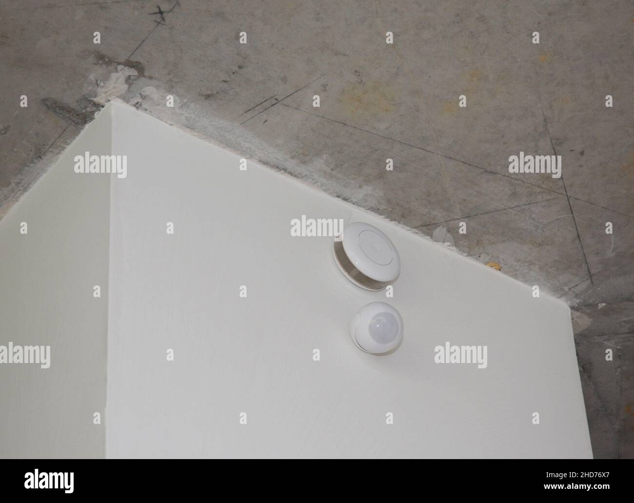A close-up of a wall with a smoke alarm system, smoke detector and dome ...