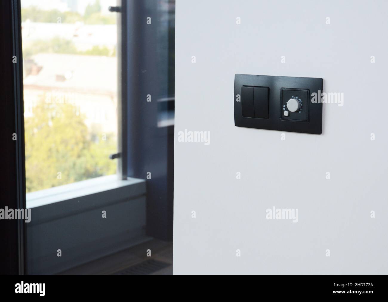 A close-up of a modern elegant black light switch and a climate ...