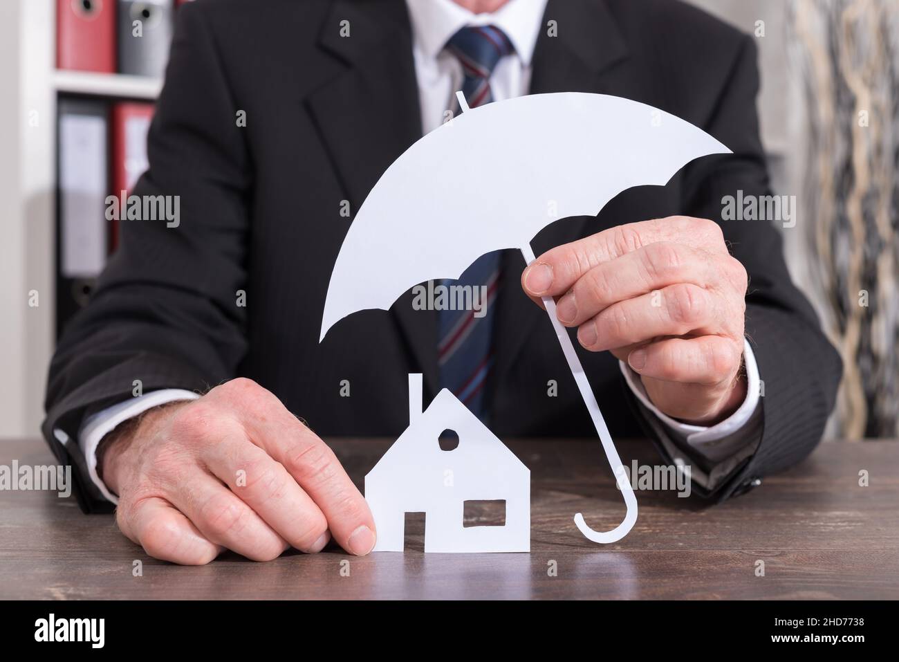 House protected with an umbrella by an insurer - insurance concept ...