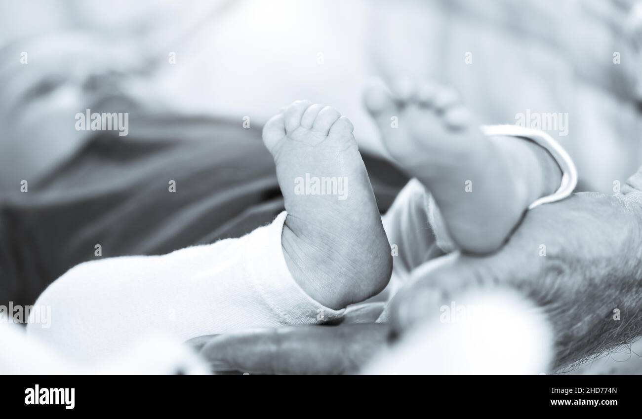 Hand of father holding the feet of his baby girl, black and white Stock ...