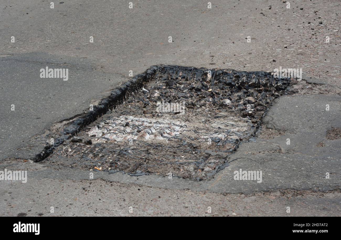 Road construction or driveway pothole repair: repairing an asphalt road ...