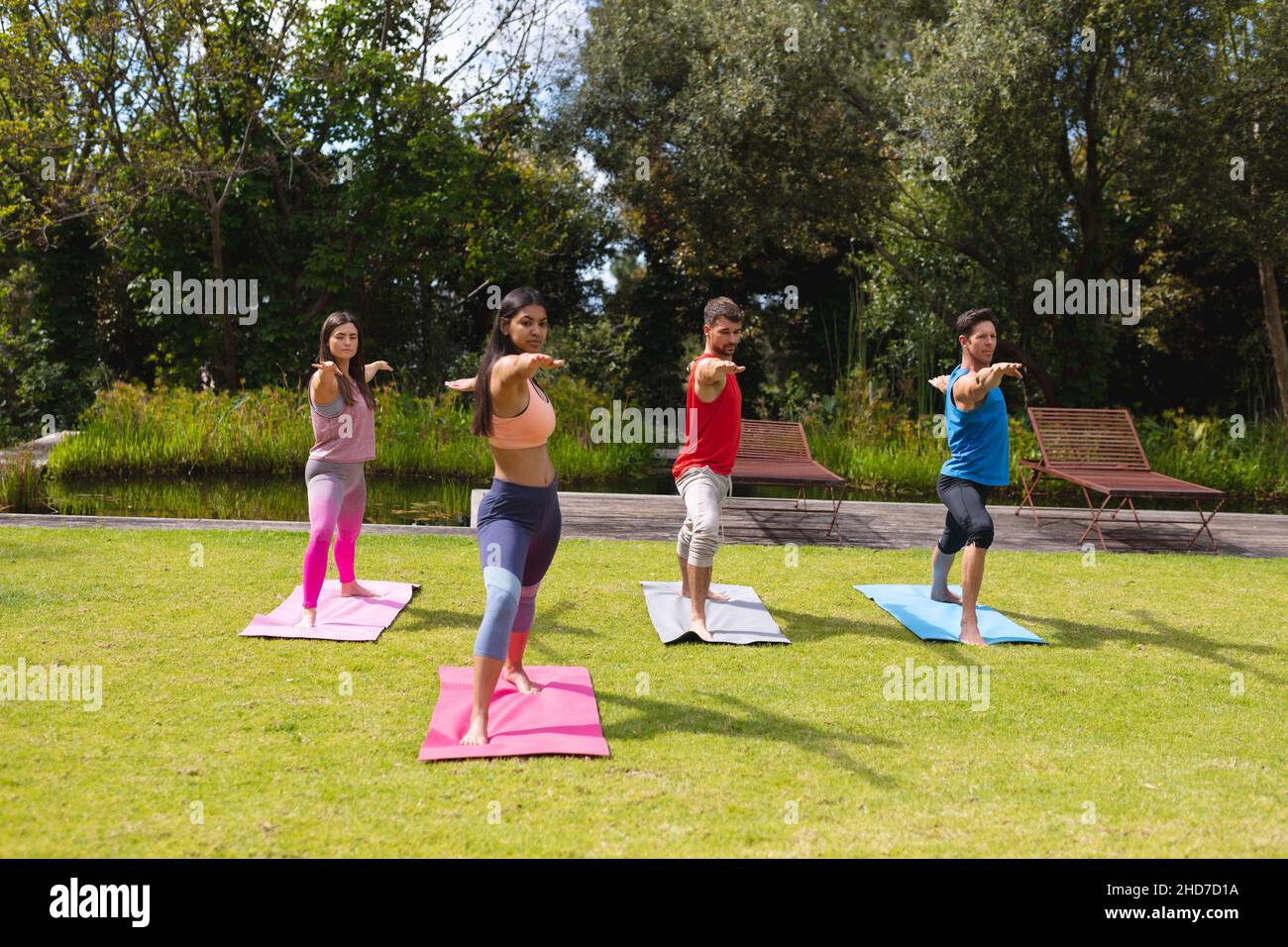 Female instructor teaching exercise to men and woman in public park ...