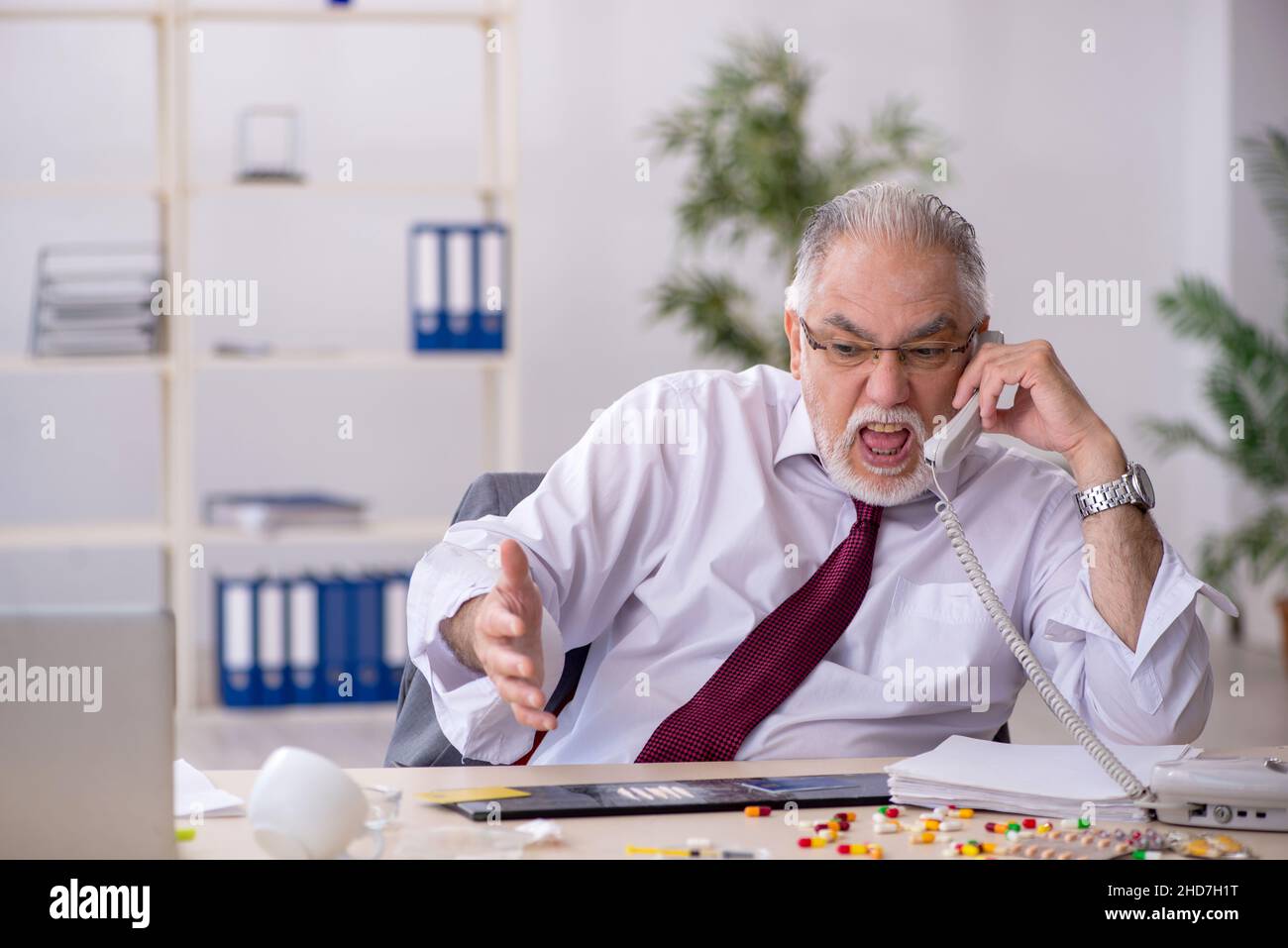 Old male drug addicted employee sitting at workplace Stock Photo - Alamy