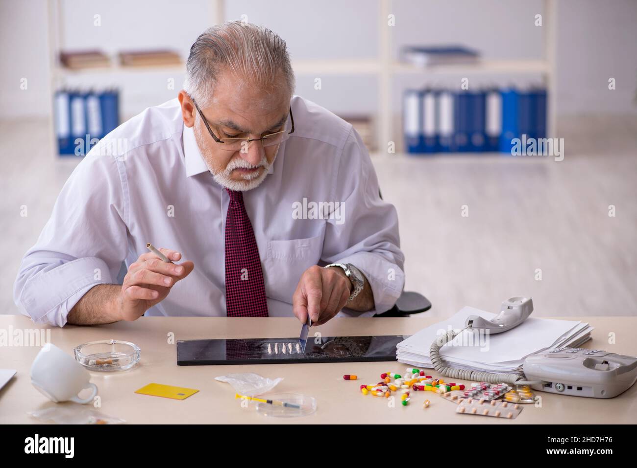 Old male drug addicted employee sitting at workplace Stock Photo - Alamy