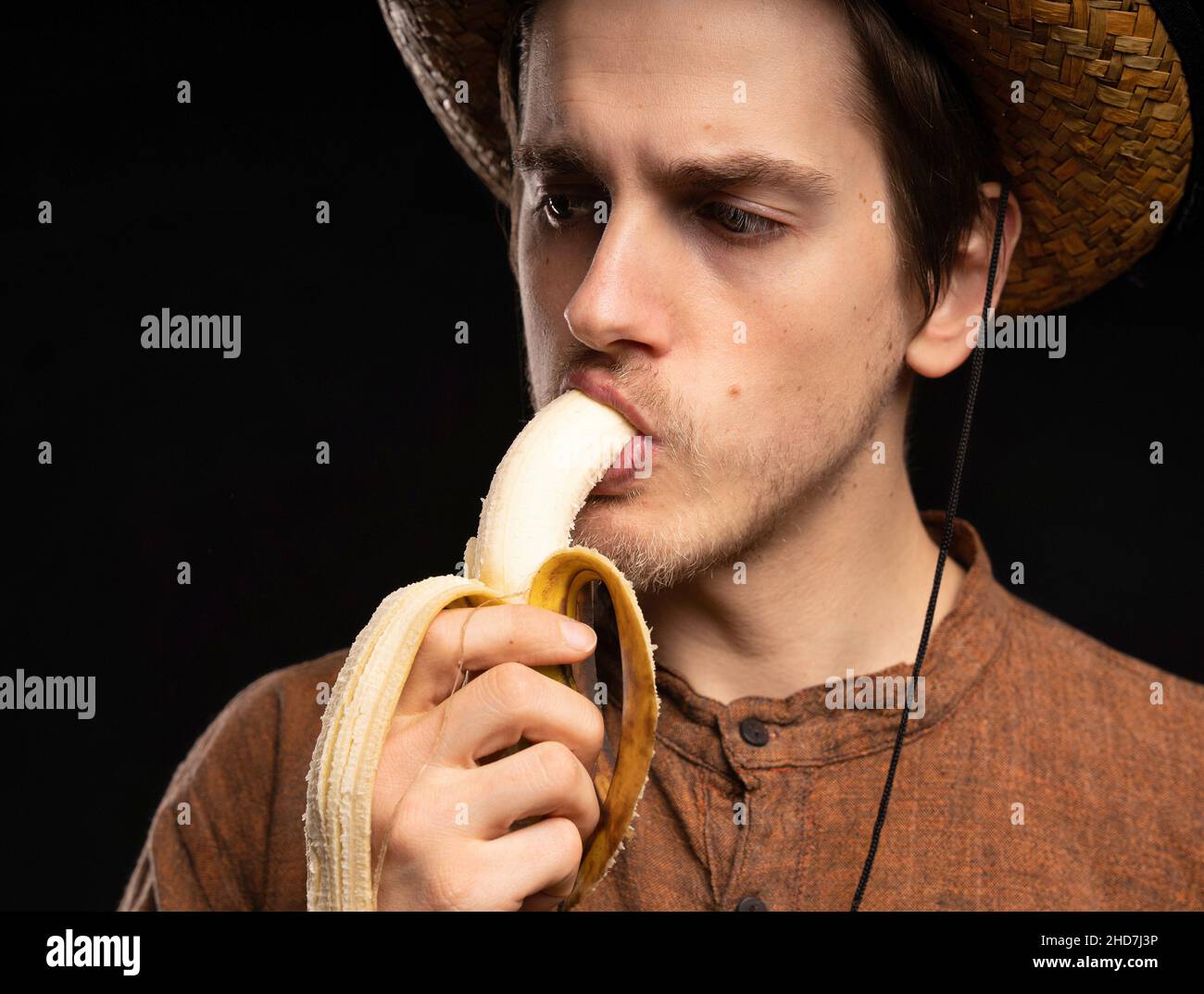 Young handsome tall slim white man with brown hair biting banana ...