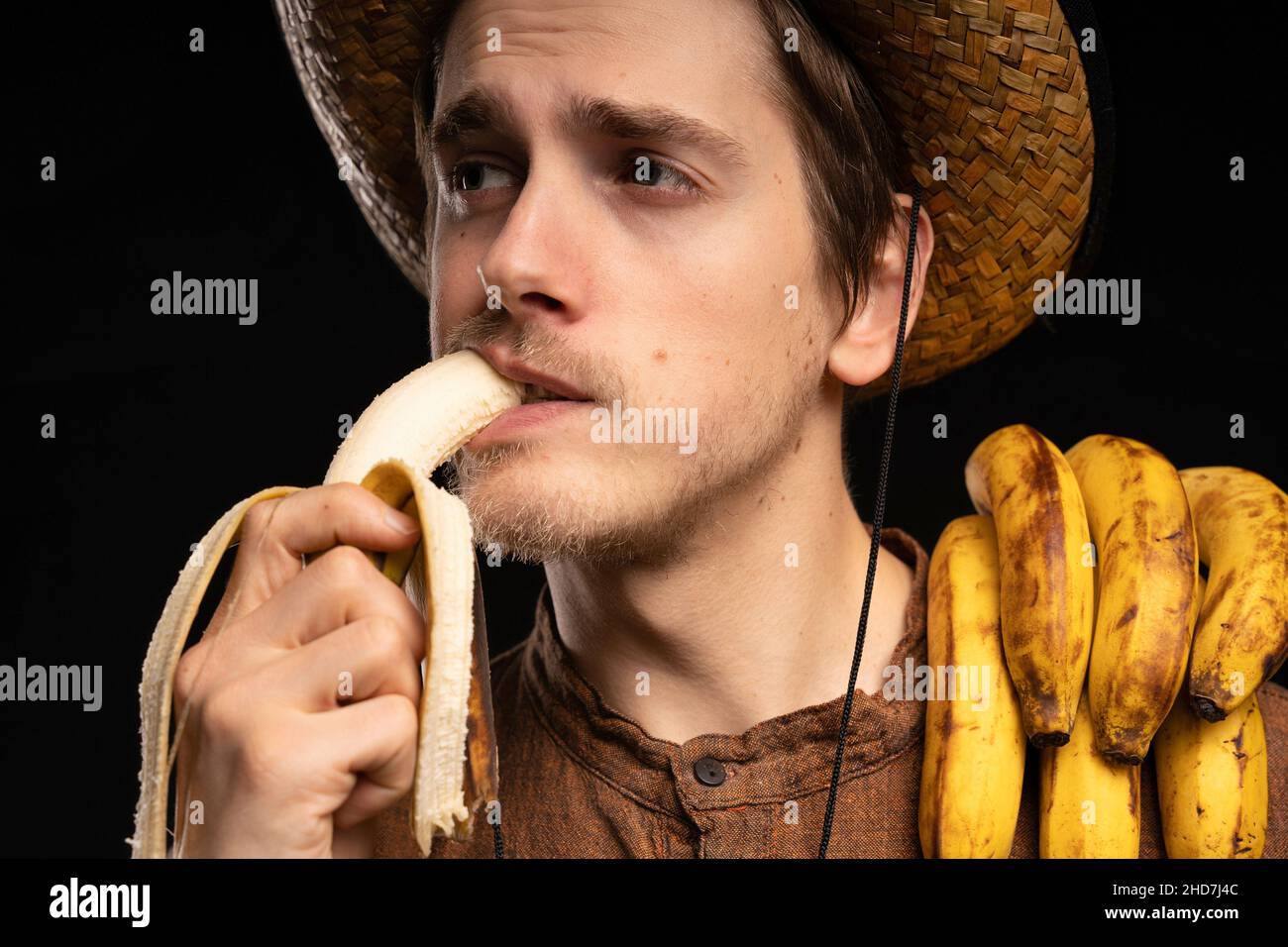 Young handsome tall slim white man with brown hair biting banana ...