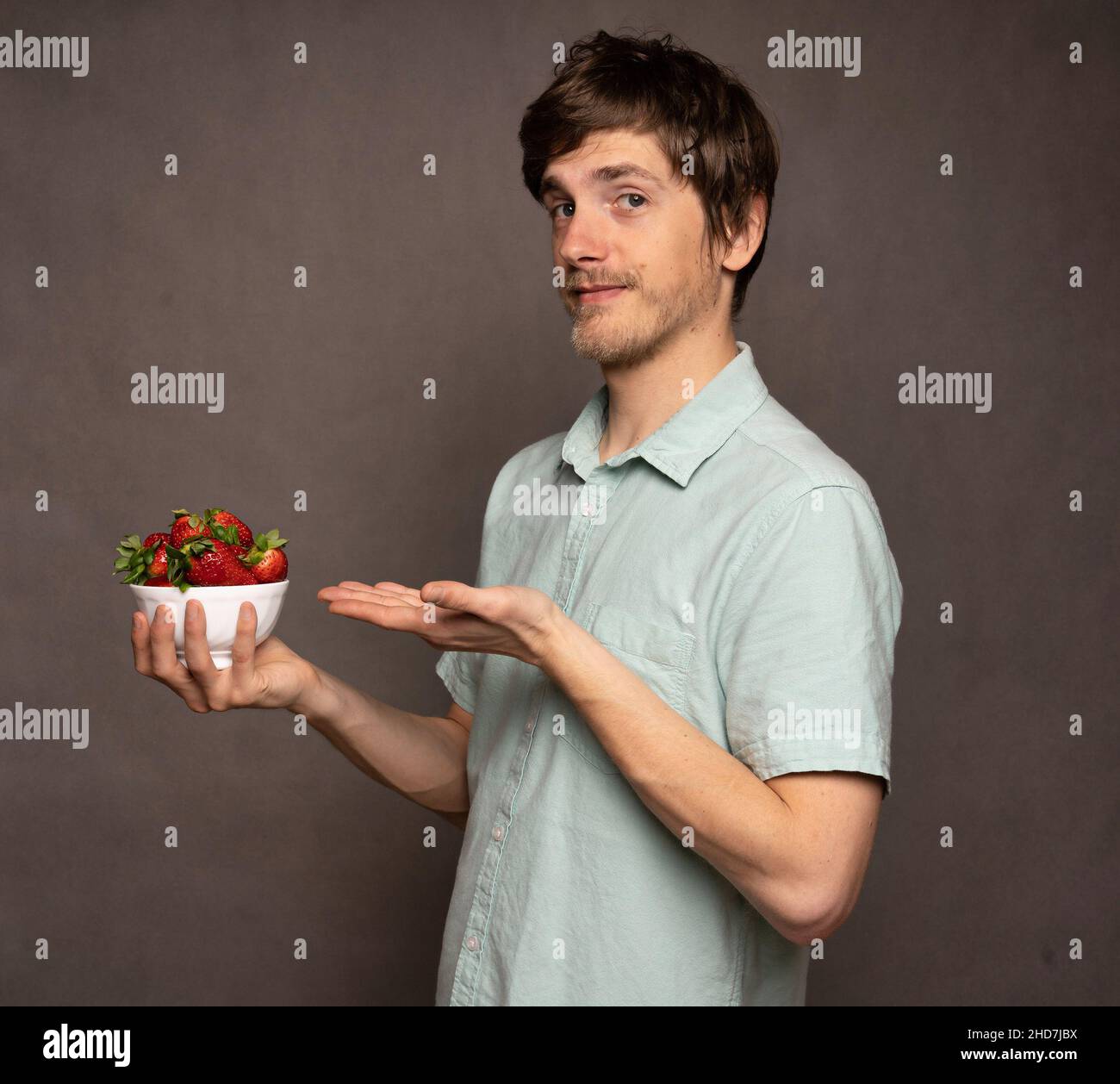 Young handsome tall slim white man with brown hair presenting bowl of ...