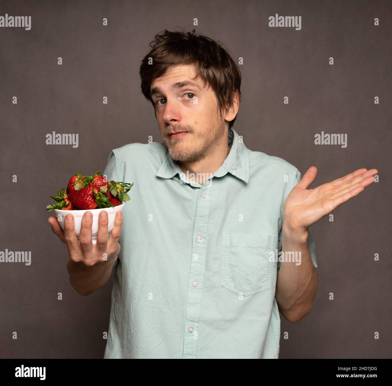 Young handsome tall slim white man with brown hair holding strawberries ...