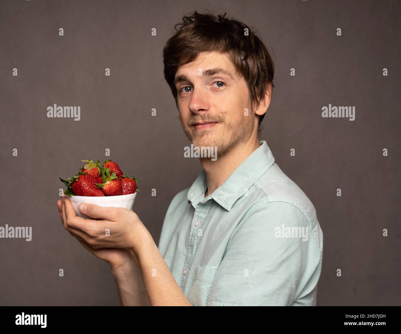 Young handsome tall slim white man with brown hair holding strawberries ...