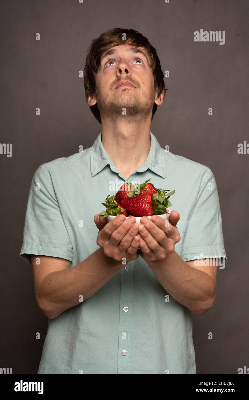 Young handsome tall slim white man with brown hair holding strawberries ...