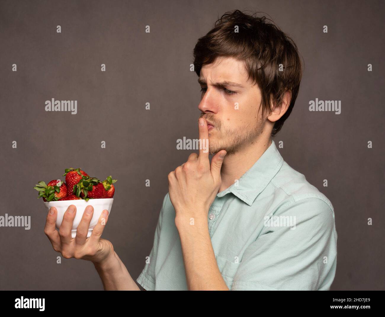 Young handsome tall slim white man with brown hair holding strawberries ...