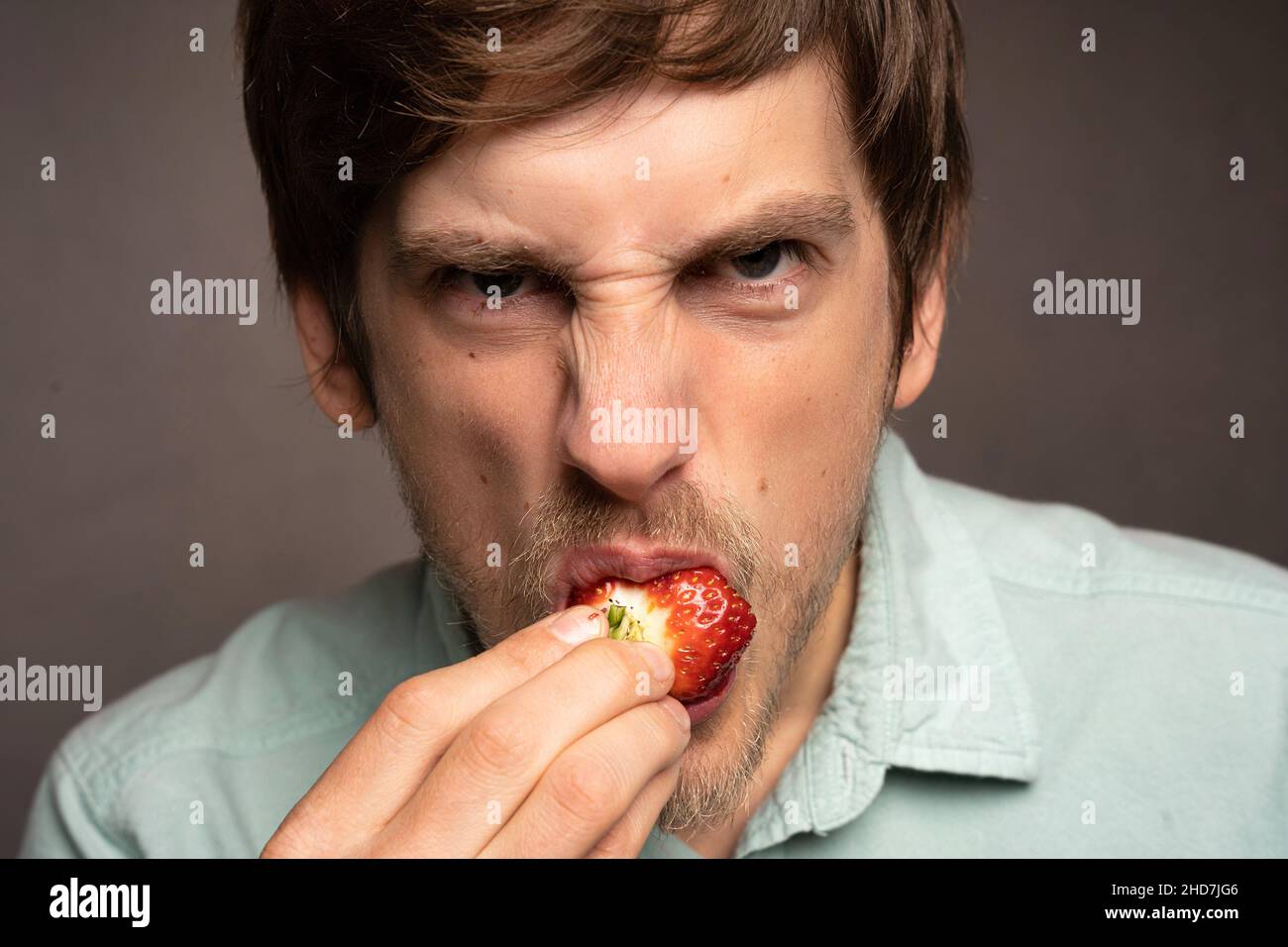 Young handsome tall slim white man with brown hair angrily biting ...