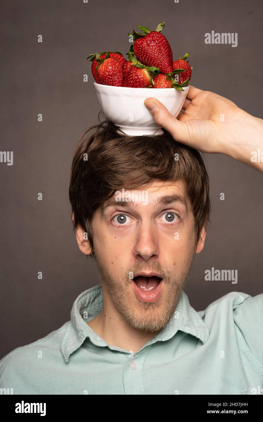 Young handsome tall slim white man with brown hair bowl of strawberries ...
