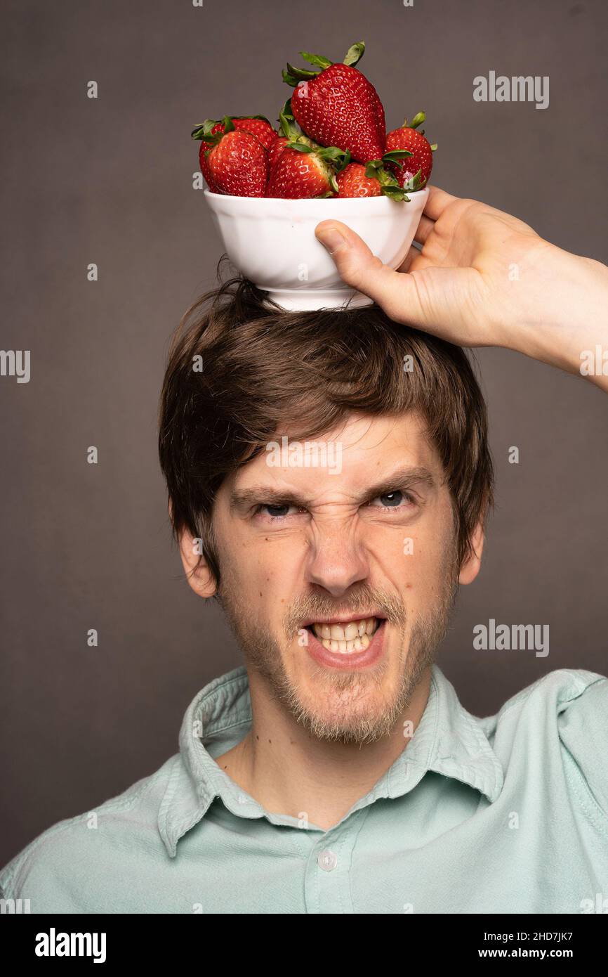 Young handsome tall slim white man with brown hair bowl of strawberries ...