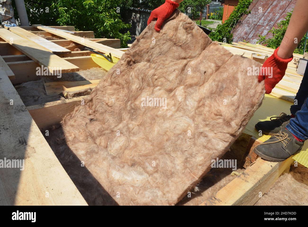 Roof insulation. A roofer is installing mineral wool insulation between ...