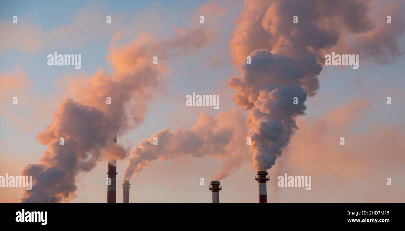 Smoky factory chimneys spectacularly illuminated by the setting sun ...