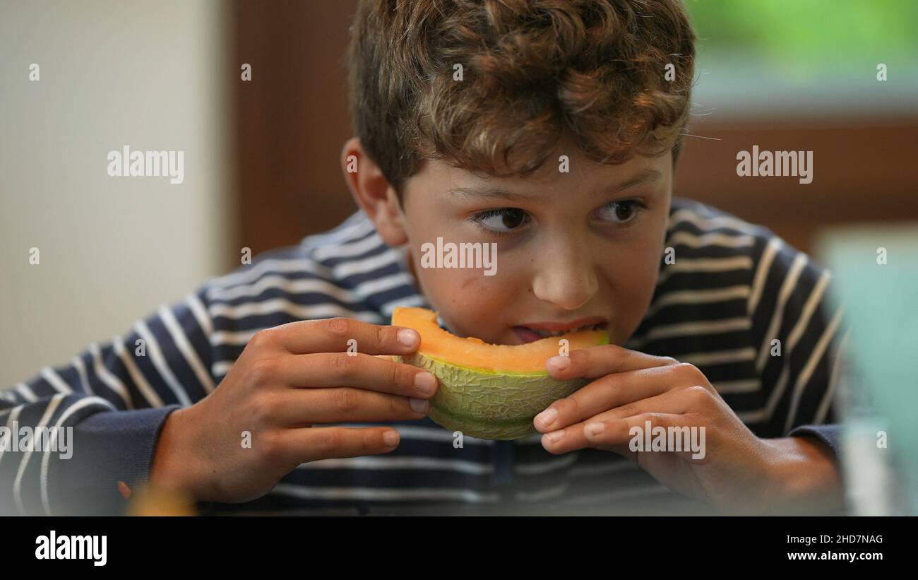Child eating melon fruit, pensive kid Stock Photo - Alamy
