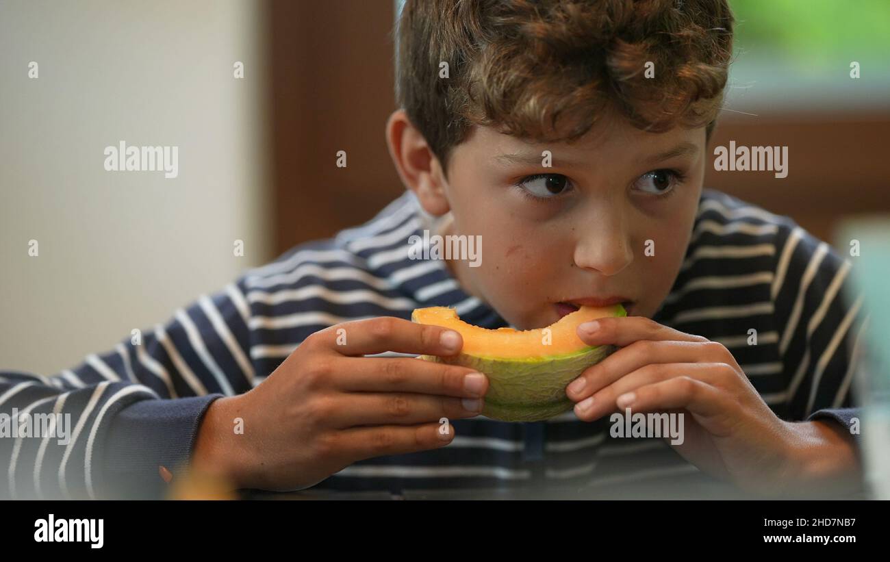 Child eating melon fruit, pensive kid Stock Photo - Alamy